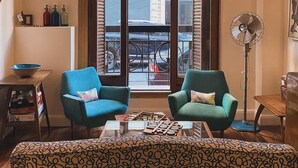 Uma sala de estar aconchegante com dois poltronas azuis, um sofá estampado, uma mesa de centro e um abajur.