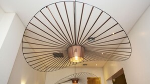 Um interior moderno com uma luminária de teto grande em formato de leque e outra menor logo abaixo.