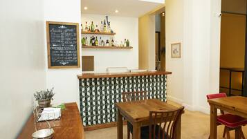 Interior de restaurante com menu em lousa, mesas de madeira, cadeiras e área de bar com prateleiras de garrafas.