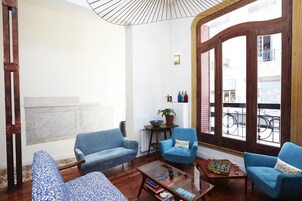Uma sala de estar com sofá, poltrona e mesa de centro com livros e um jogo de tabuleiro.