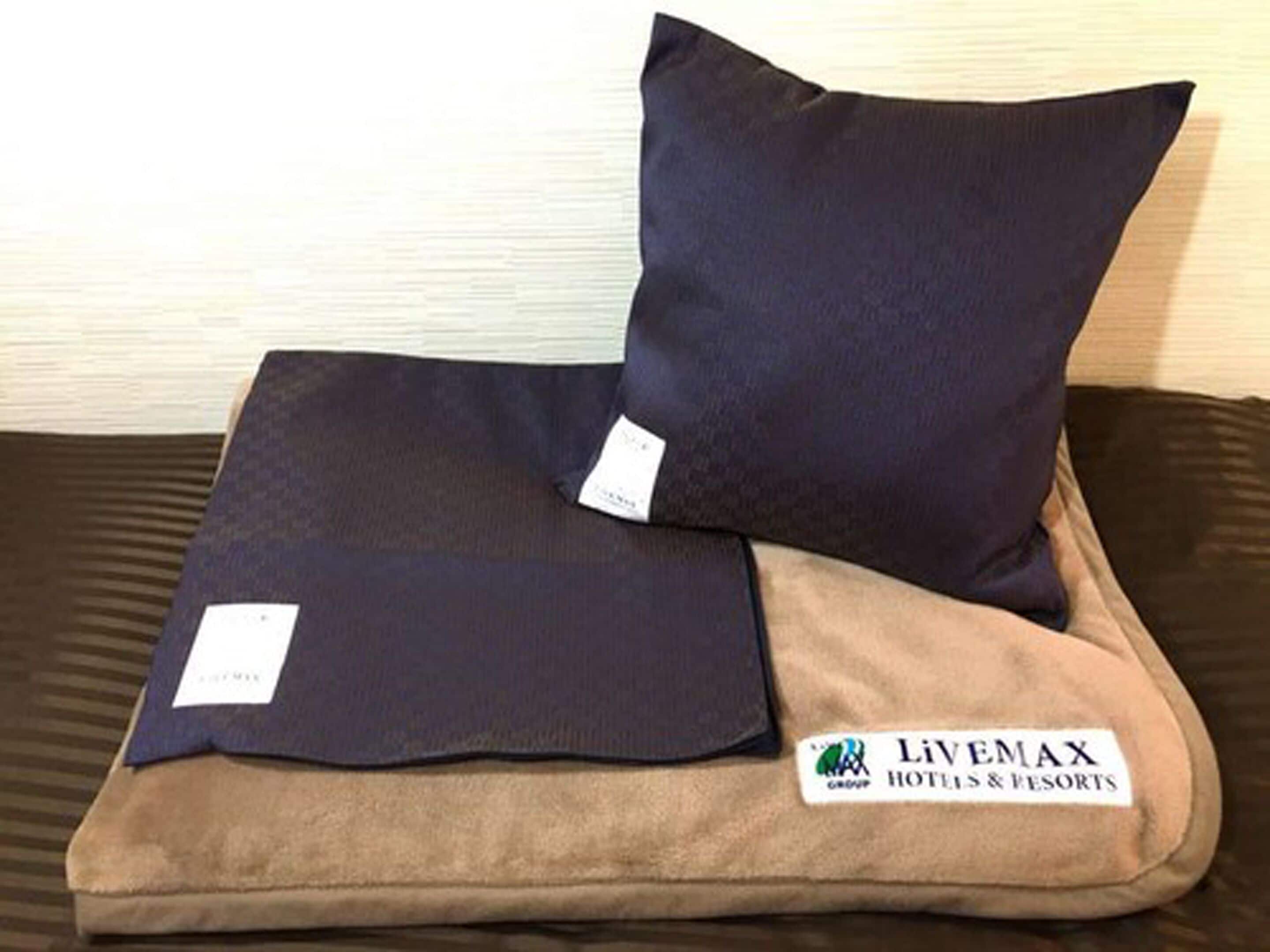 Cama com travesseiro azul escuro e cobertor marrom com etiqueta.