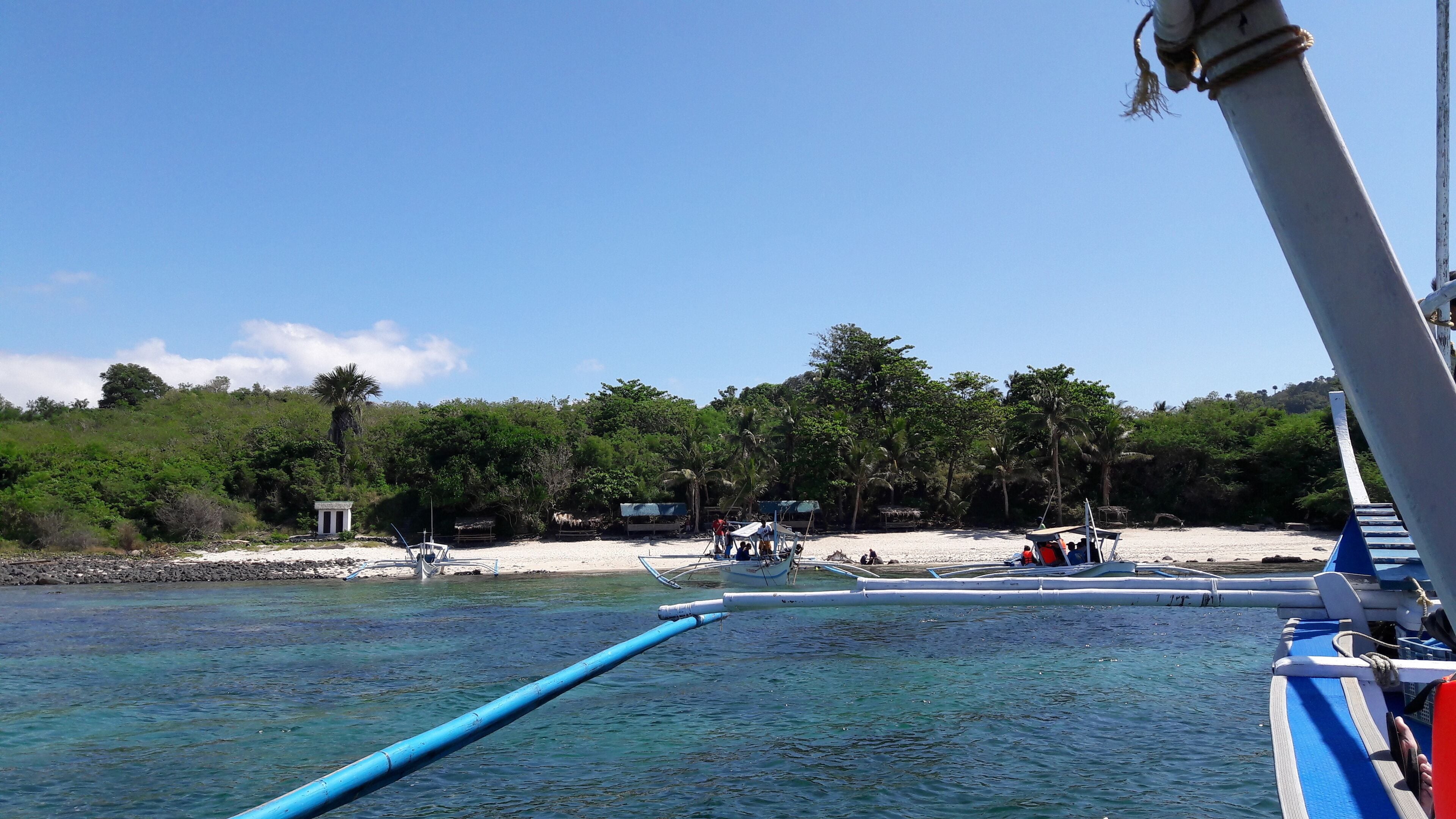 Uma praia com águas cristalinas e um barco atracado perto.
