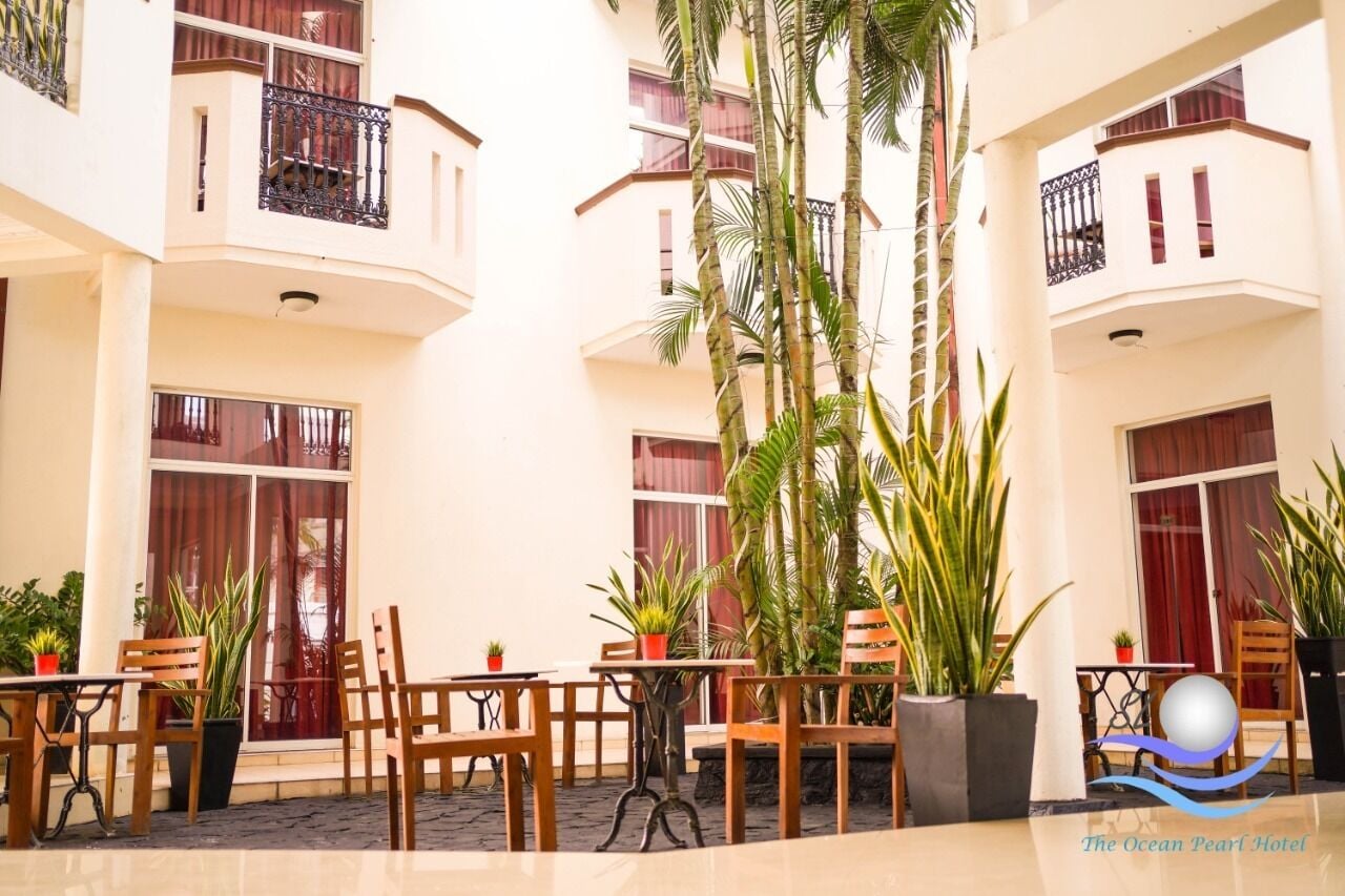 Pátio de hotel com várias varandas, plantas em vasos e áreas de estar ao ar livre.