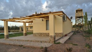 Um edifício com pérgola, pilares de pedra e uma janela pequena.