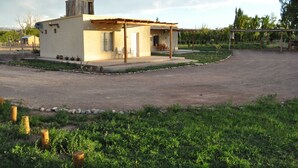 Uma casa térrea com um pátio, um pequeno jardim e um caminho de terra.