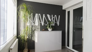 Decoração moderna com parede preta, balcão de recepção branco e um vaso de planta.