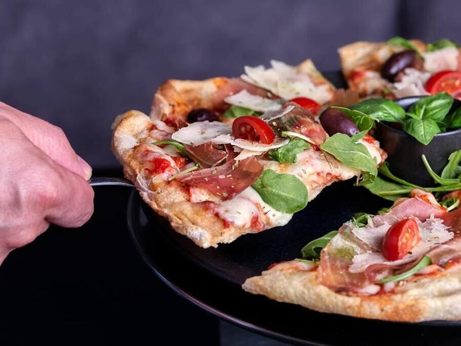 Pizza com cobertura de presunto, queijo e folhas.