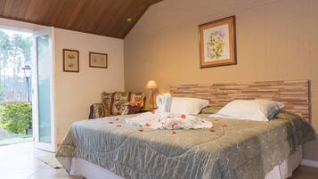 Quarto com teto de madeira, cama com colcha florida, abajur e quadro na parede.