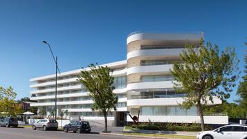 Um edifício de vários andares com design arquitetônico moderno, com varandas e grandes janelas.