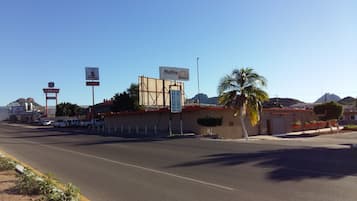 Um hotel chamado 'Malibu Hotel', com uma placa, uma palmeira e um céu claro.