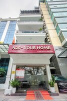 Entrada de hotel com placa vermelha que diz 'A25 - SEU LAR', informações de contato e porta de vidro.