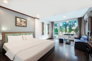 Quarto de hotel com uma cama grande, um sofá, uma mesa de centro e um quadro na parede.