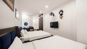 Quarto de hotel com duas camas, televisão, relógio e espelho.