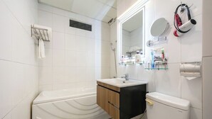 Um banheiro moderno com banheira, vaso sanitário, pia com espelho e chuveiro.