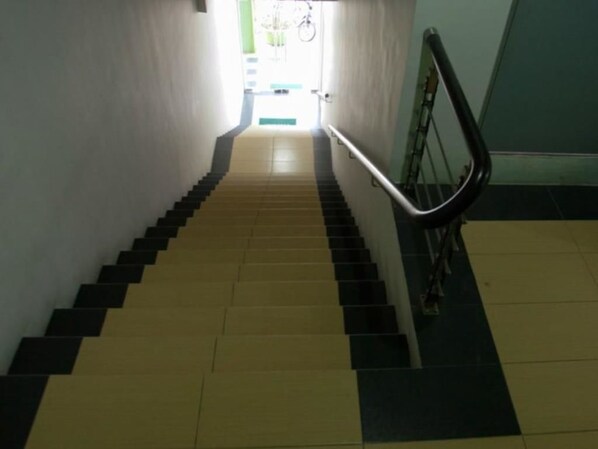 Escadaria com degraus alternados em preto e amarelo, levando a uma porta no topo.