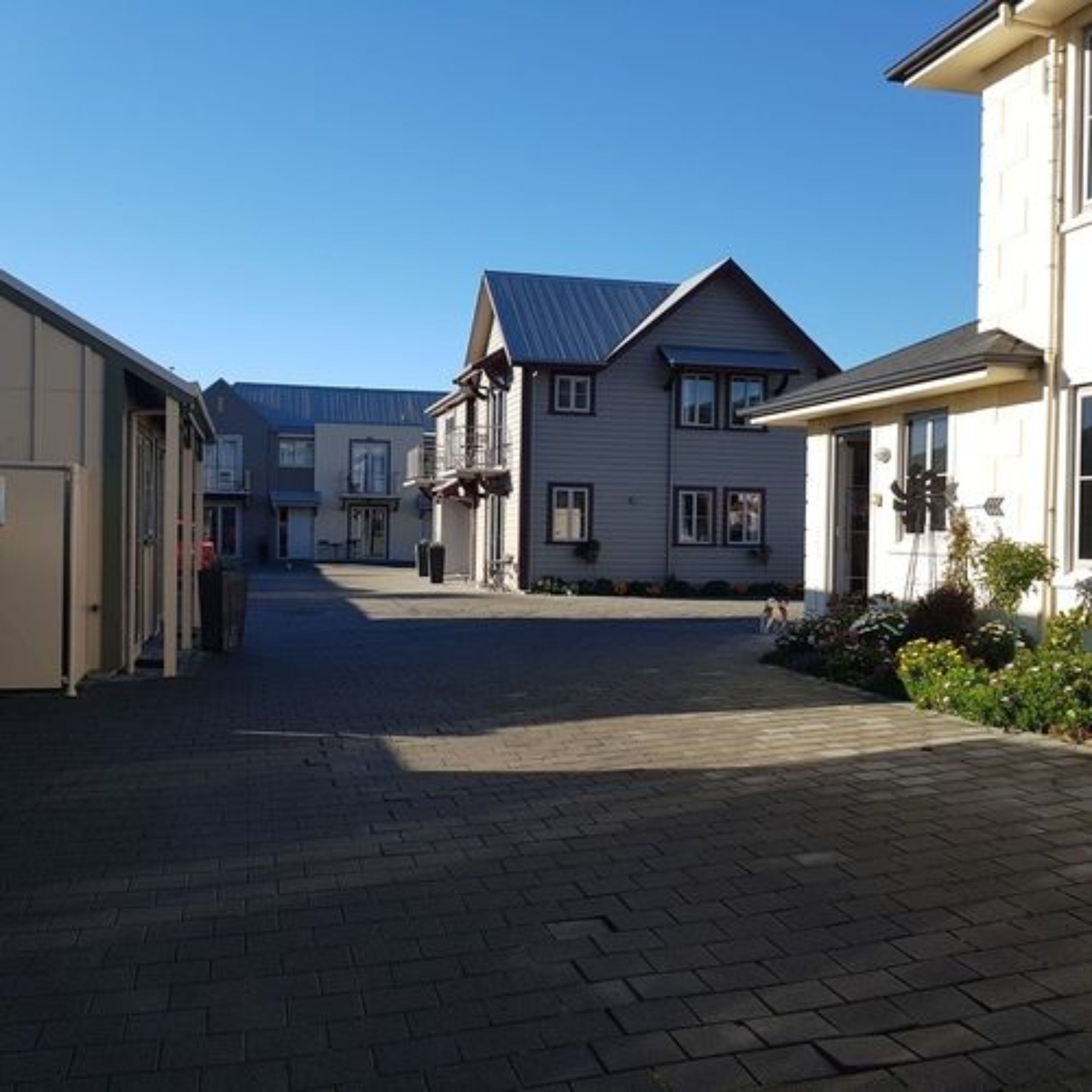 Rua residencial com casas, um calçada pavimentada e céu claro.