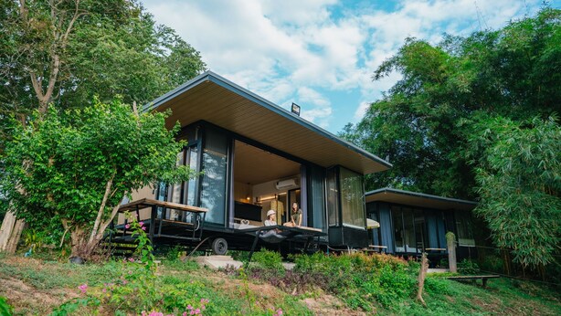 Uma casa moderna com um alpendre amplo, cercada por vegetação exuberante.