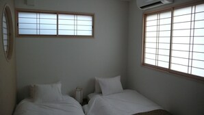 Quarto com duas camas, um espelho e janelas com molduras de madeira.