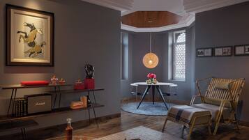 Uma sala de estar moderna com uma mesa redonda, uma cadeira de vime, uma mesa de centro de vidro e uma estante.