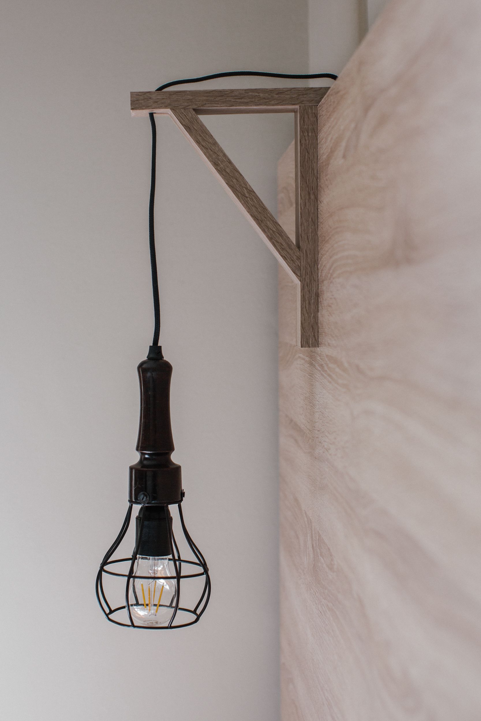 Uma luminária pendente com lâmpada de vidro transparente e fio preto.