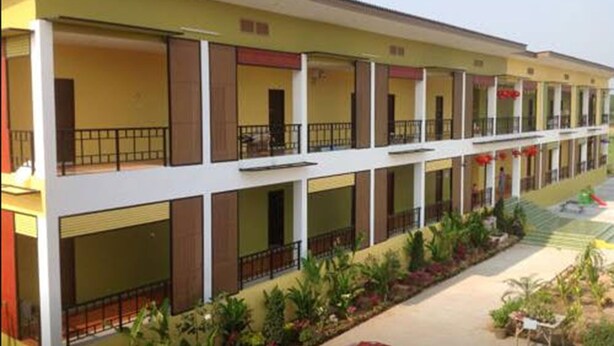Um hotel com vários andares, varandas, galeria coberta e área de jardim ajardinada.