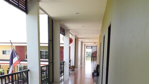Um corredor com piso de azulejos, um corrimão de um lado e uma bandeira do outro.