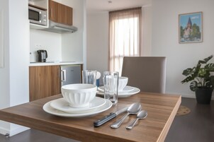 Uma cozinha moderna com armários de madeira, micro-ondas e uma mesa de jantar posta com pratos, tigelas, copos e talheres brancos.