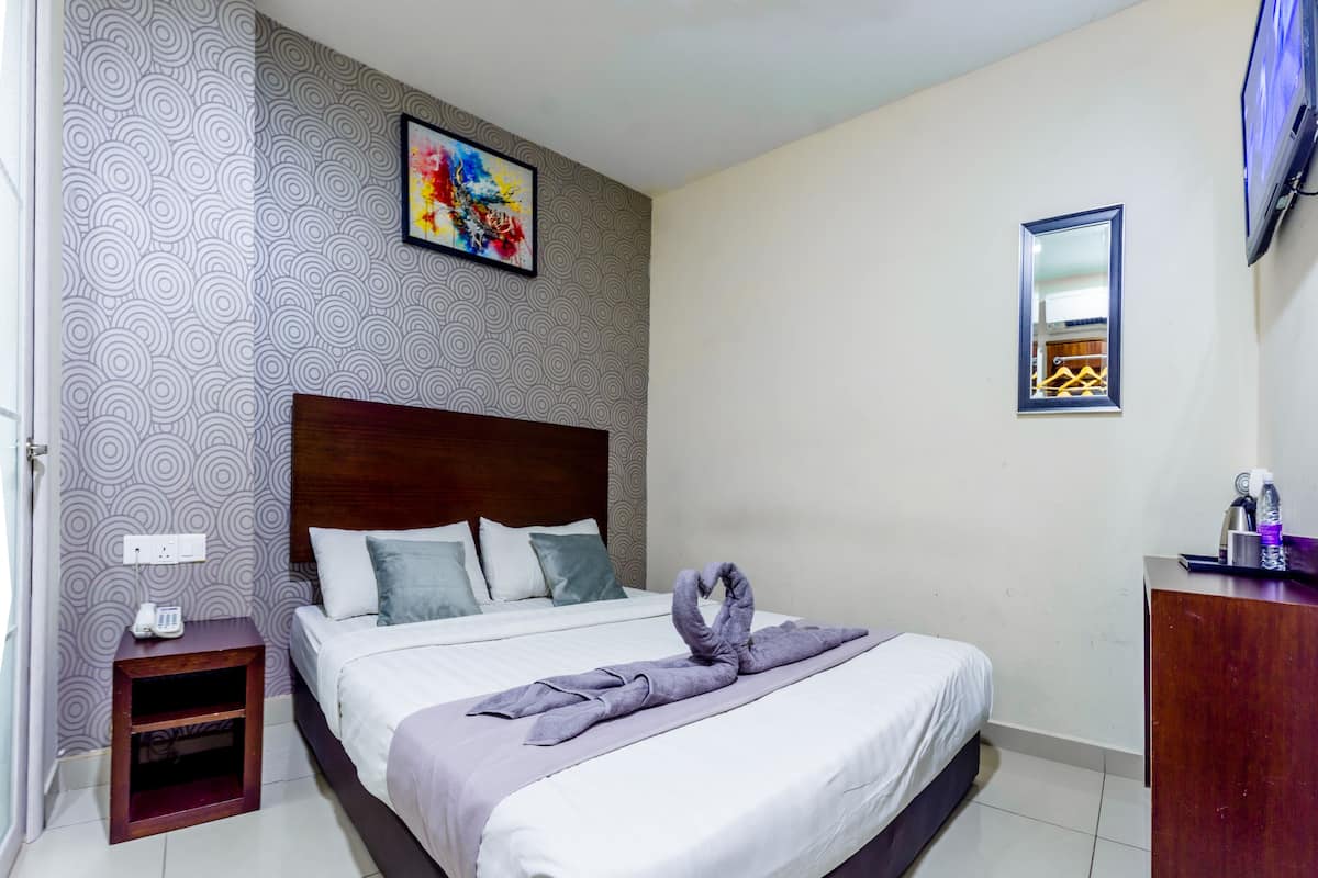 Quarto de hotel com cama, mesa de cabeceira, televisão na parede, espelho e quadro.