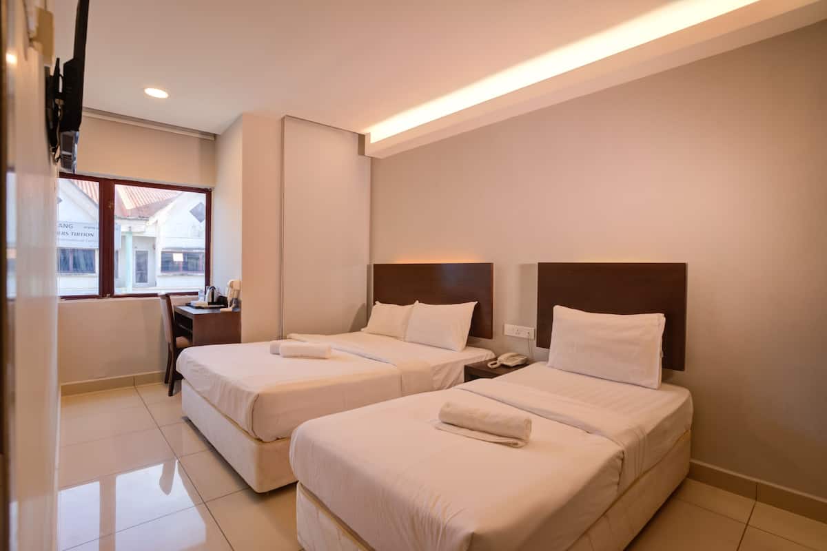 Quarto de hotel com duas camas, uma escrivaninha e uma cadeira.