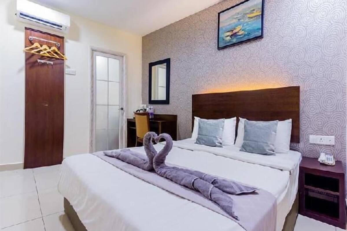 Quarto de hotel com cama, penteadeira, espelho e um quadro na parede.