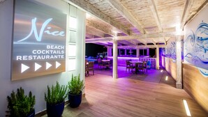 Restaurante de cocktails à beira-mar, com teto de madeira e um espaço de bar.