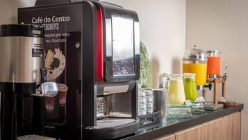 Uma máquina de café com visor e dispensador de café, ao lado de um dispensador de bebidas com opções coloridas.