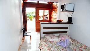 Quarto com uma cama, uma cadeira, um micro-ondas e uma janela.