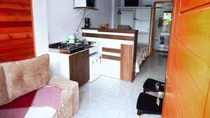 Cozinha compacta com fogão a gás, micro-ondas e pia. Uma pequena área de refeições com mesa e cadeiras é visível.