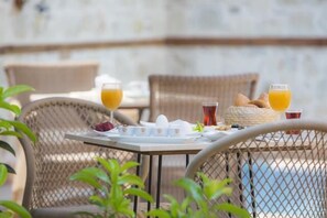 Disposição para o pequeno-almoço com croissants, sumo de laranja e chá, numa mesa com vista para a piscina.