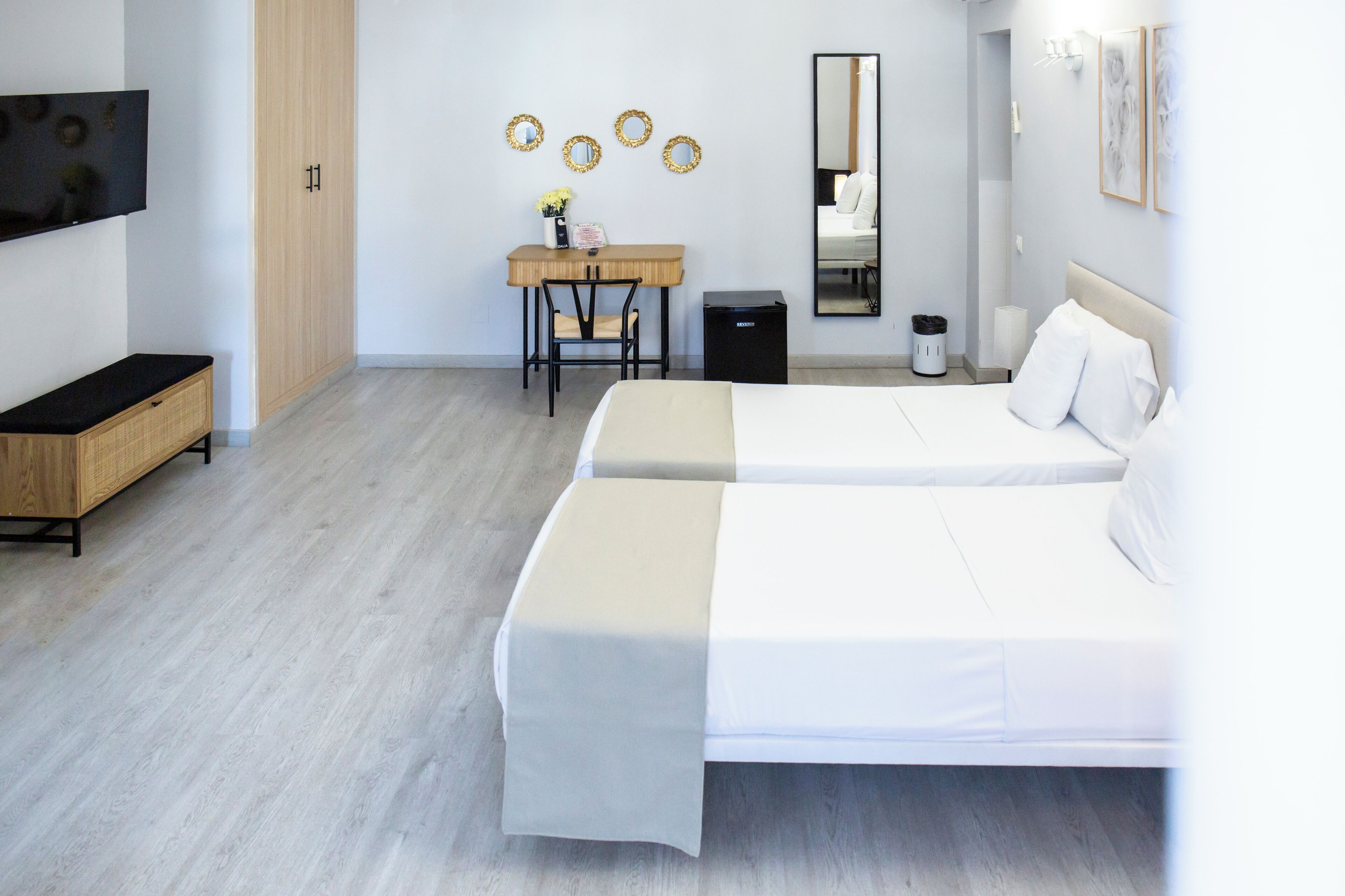 Quarto de hotel com cama, escrivaninha e televisão.