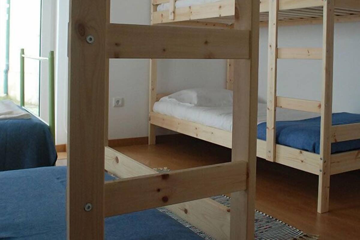 Quarto com beliches de madeira e roupa de cama azul.
