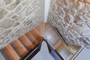 Um canto do quarto com parede de pedra e soalho de madeira.