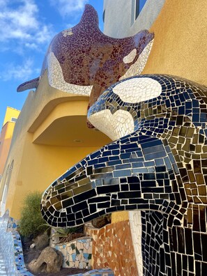 Uma escultura em mosaico de um pássaro com bico curvo, em frente a uma fachada de edifício.
