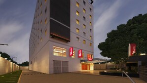 Um hotel moderno com design vertical marcante, diversas janelas e uma entrada bem iluminada.