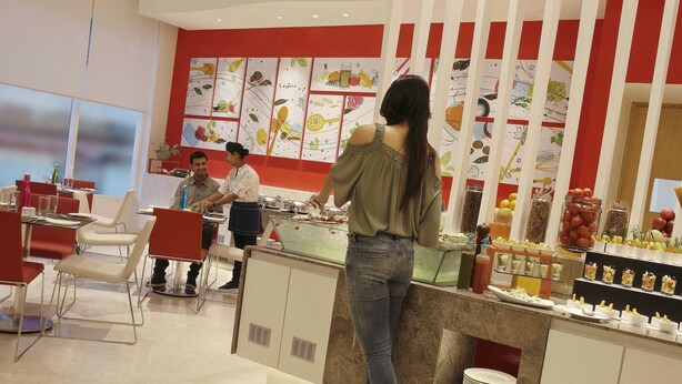 Restaurante moderno com decoração em vermelho e branco, um balcão de buffet e arranjos de mesas.