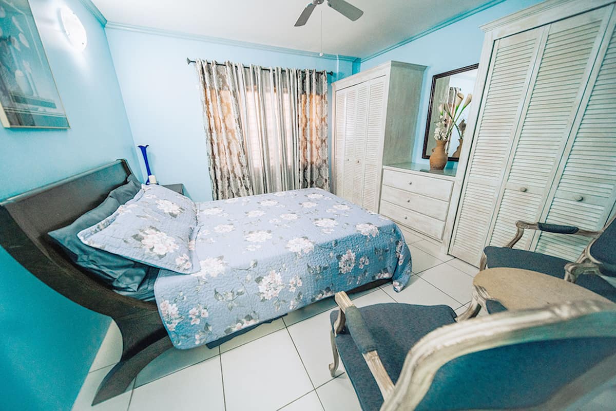 Quarto com cama, cadeira, guarda-roupa e ventoinha no teto.