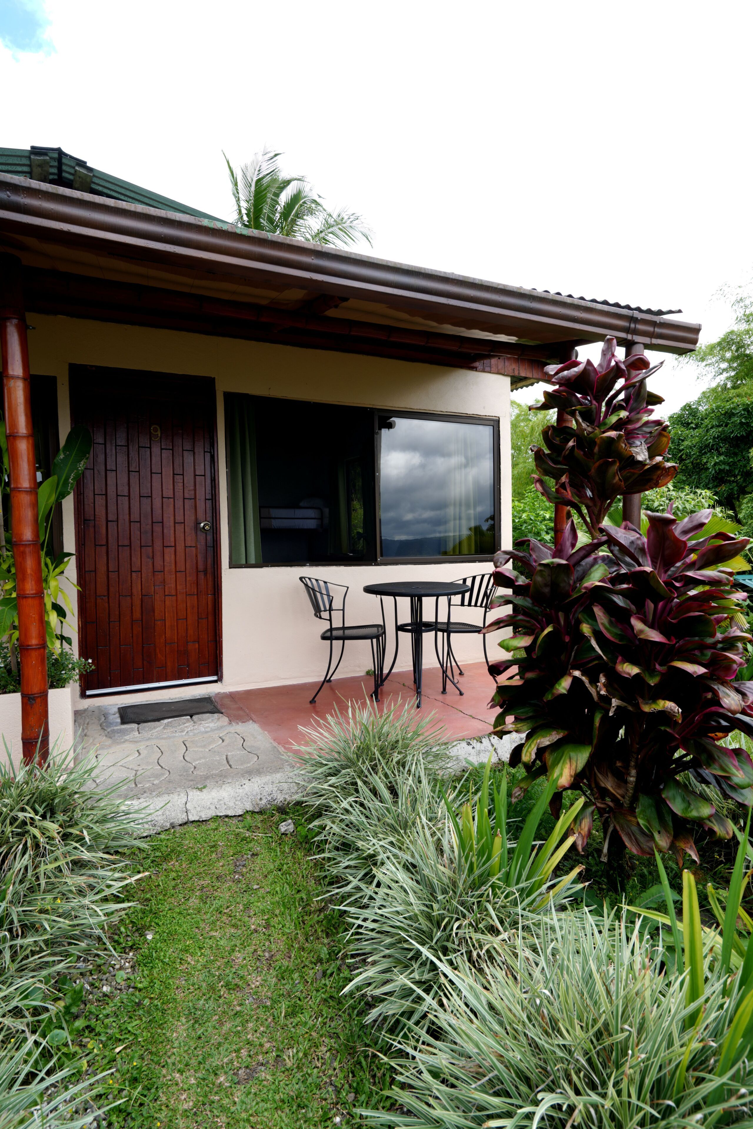 Uma casa com porta de madeira, janela e um pátio com mesa e cadeiras.