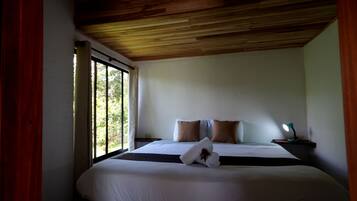 Um quarto com uma cama grande, uma mesa de cabeceira com abajur e uma janela com cortinas.