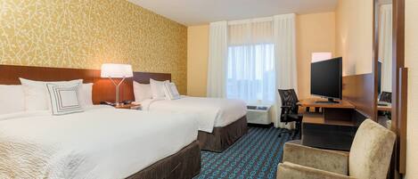 Quarto de hotel com duas camas, uma escrivaninha com computador, televisão e uma cadeira.