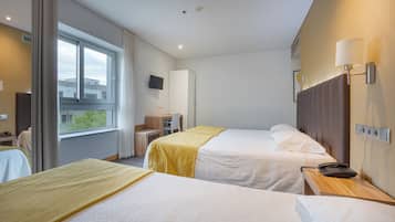 Quarto de hotel com duas camas, uma escrivaninha, uma cadeira, uma televisão e uma janela com cortinas.