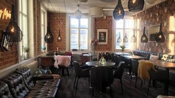 Um restaurante acolhedor com paredes de tijolo, assentos de couro, luminárias pendentes e uma janela grande.