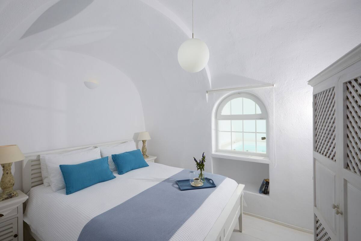 Um quarto bem arrumado com cama, mesas de cabeceira, janela e guarda-roupa.