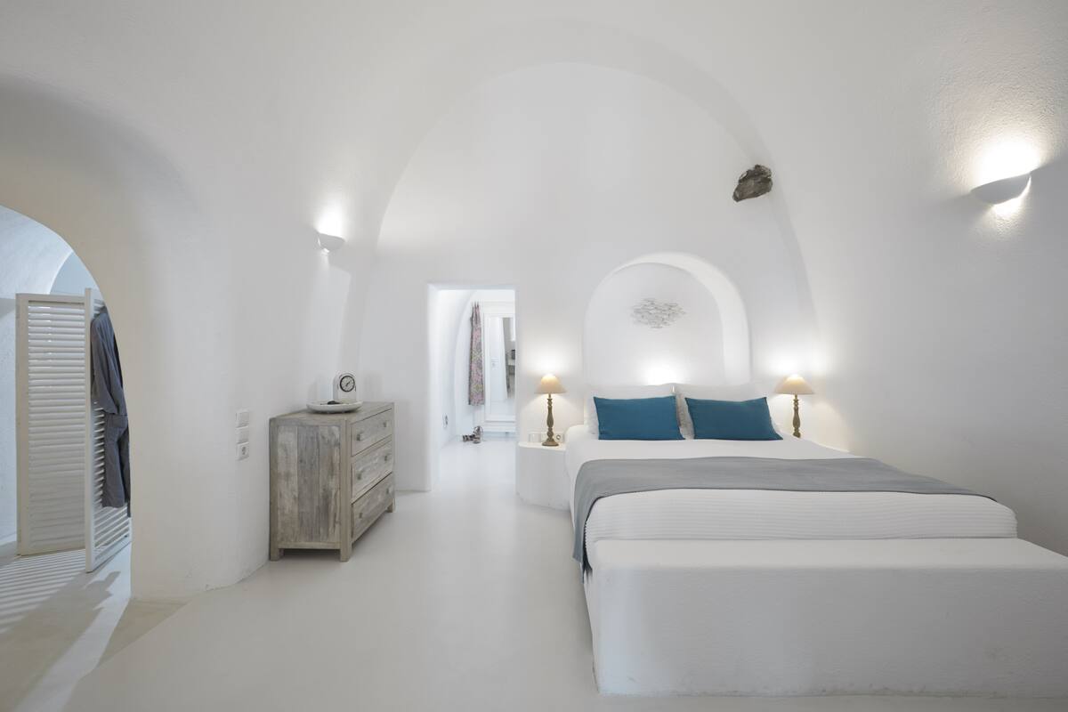 Quarto com uma cama grande, uma cômoda de madeira e uma mesa de cabeceira com abajur.