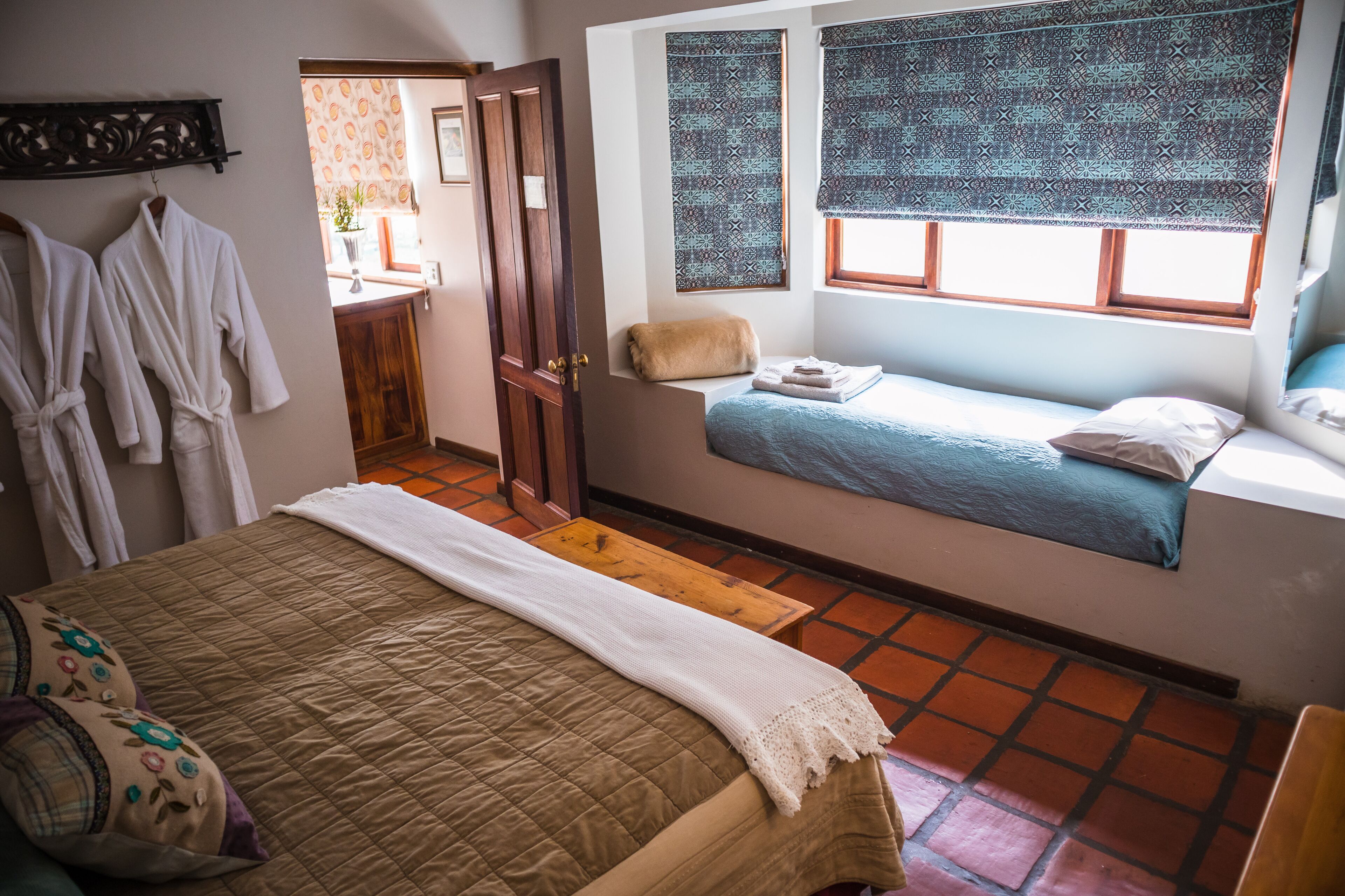 Quarto com cama, janela com vista, mesa de cabeceira e prateleira na parede com toalhas.